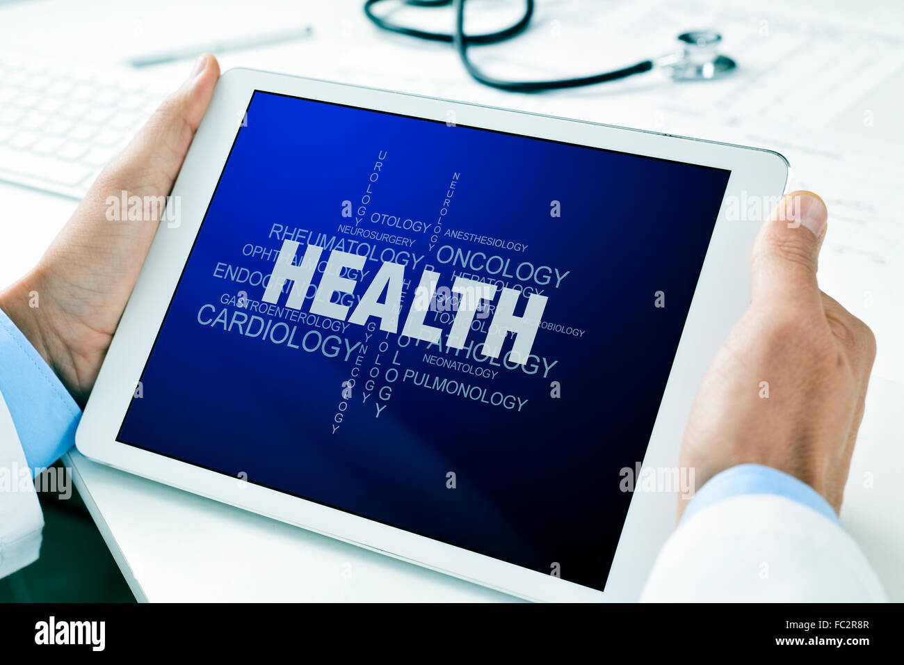 closeup of a doctor man sitting at his office desk holding a tablet ...