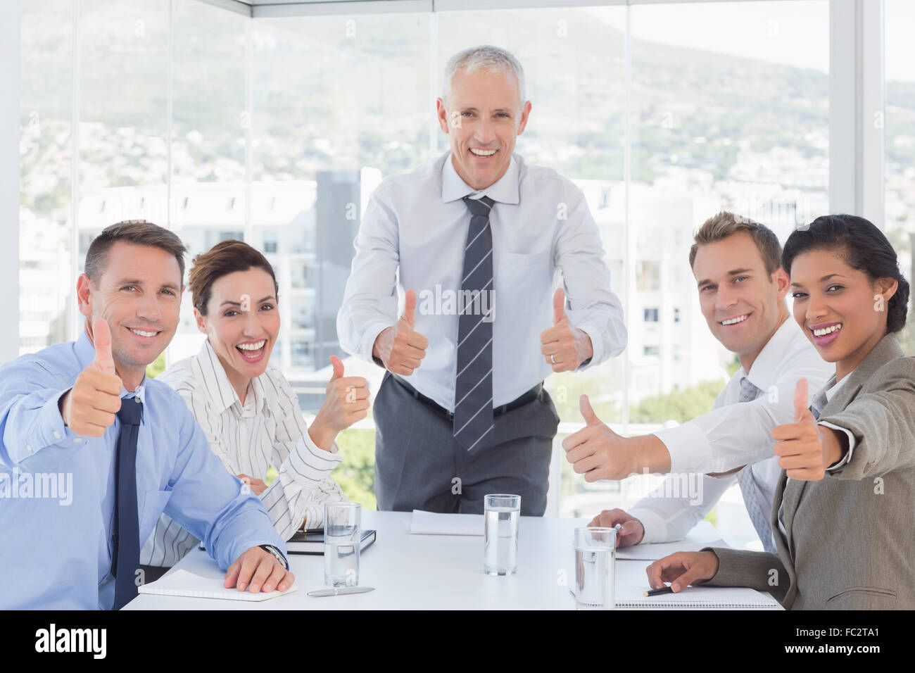 Business team smiling at camera showing thumbs up Stock Photo - Alamy
