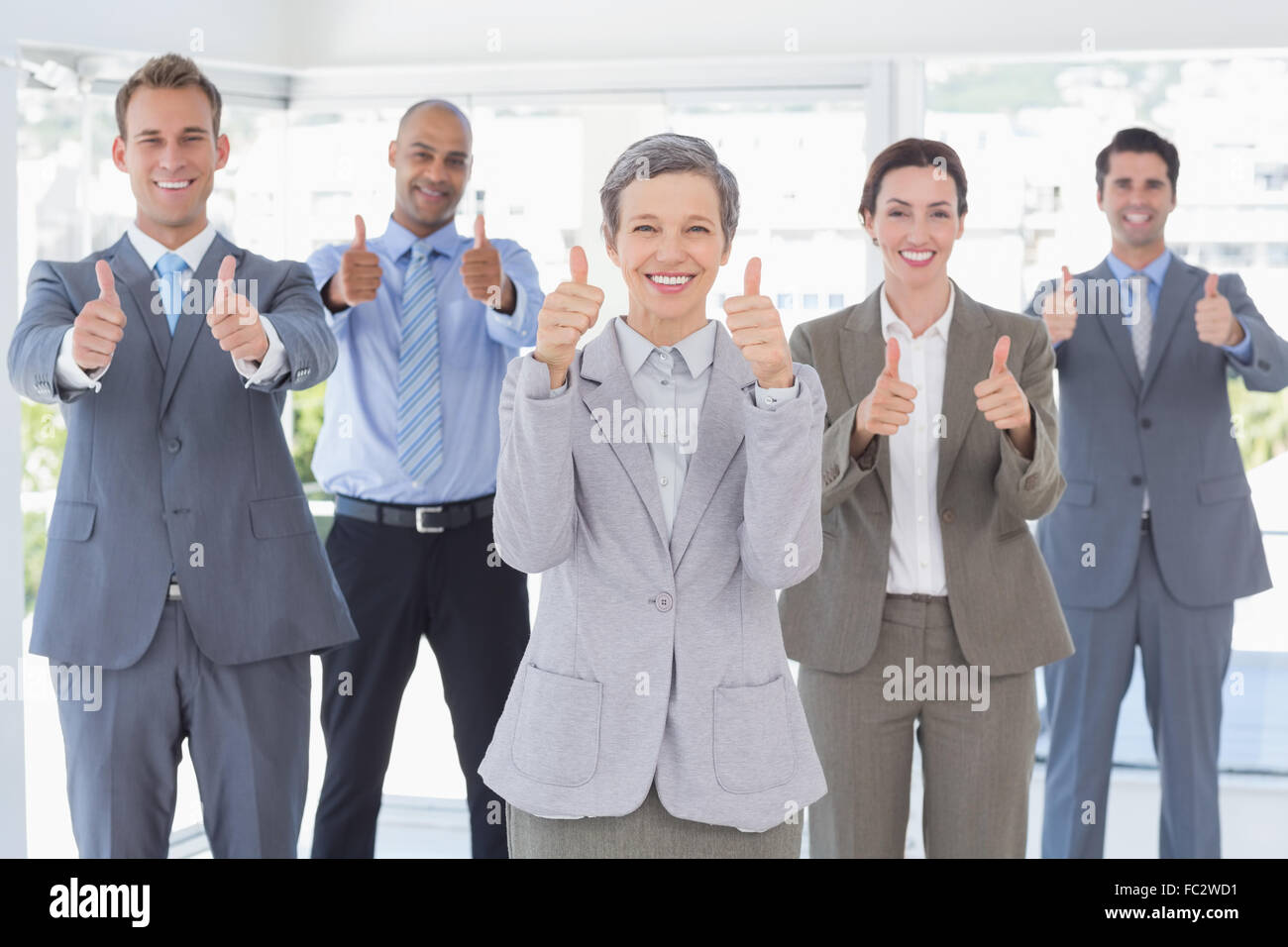 Business team smiling at camera showing thumbs up Stock Photo - Alamy