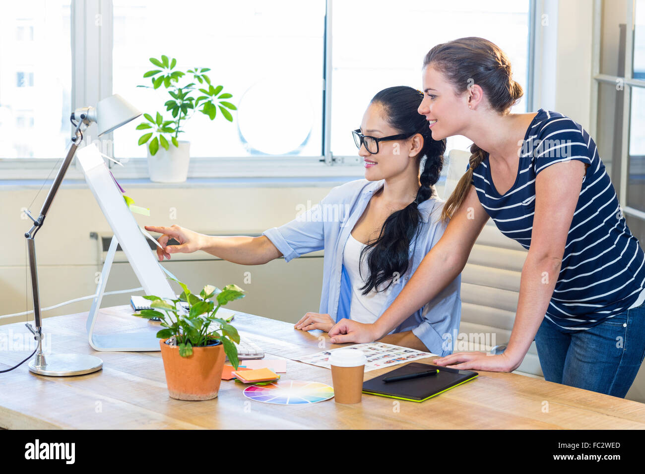 Smiling partners working together with photographs on computer Stock ...