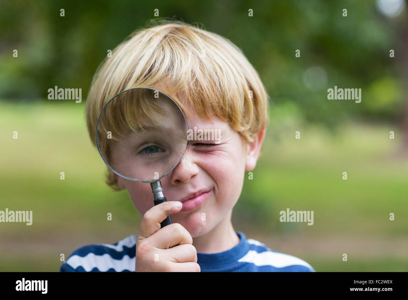 Curious little boy looking through magnifying glass Stock Photo - Alamy