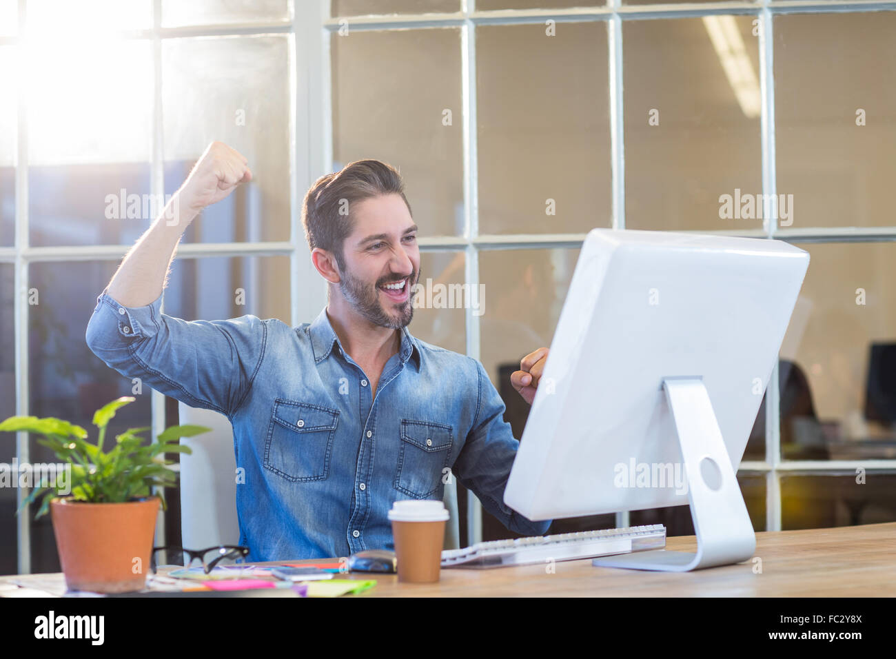 Casual businessman cheering in front of his computer Stock Photo - Alamy
