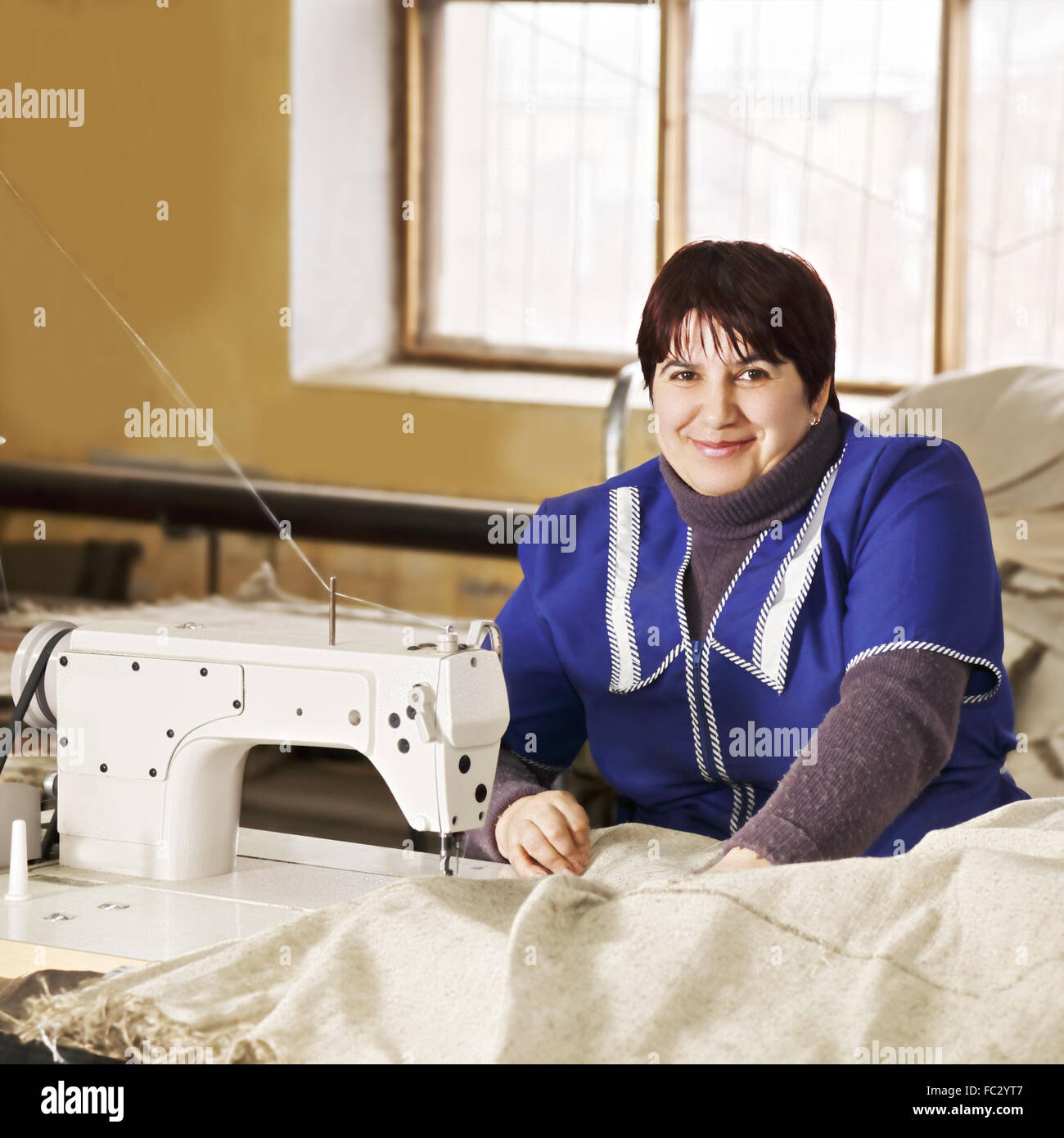 Smiling seamstress in blue smock Stock Photo - Alamy