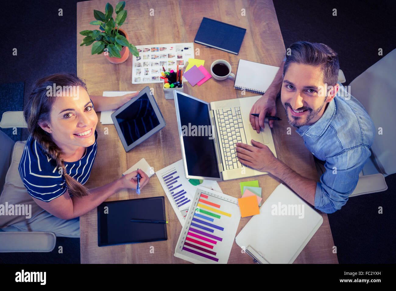 Happy creative workers sharing desk Stock Photo - Alamy
