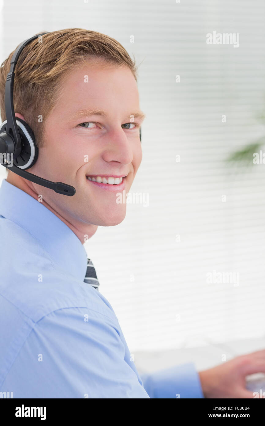 Handsome agent with headset typing on keyboard Stock Photo - Alamy