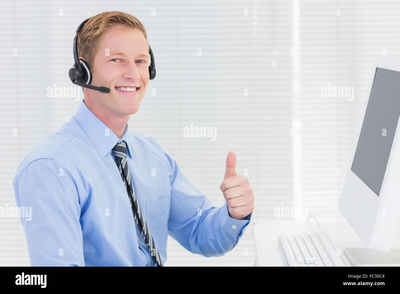Handsome agent with headset smiling at camera Stock Photo - Alamy