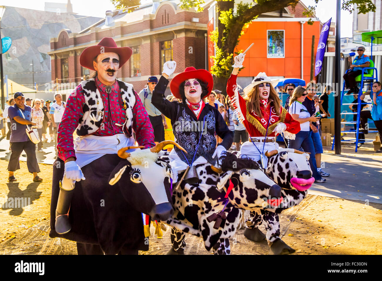 Costumed performers dressed as cowboys and cowgirls riding puppet cows ...