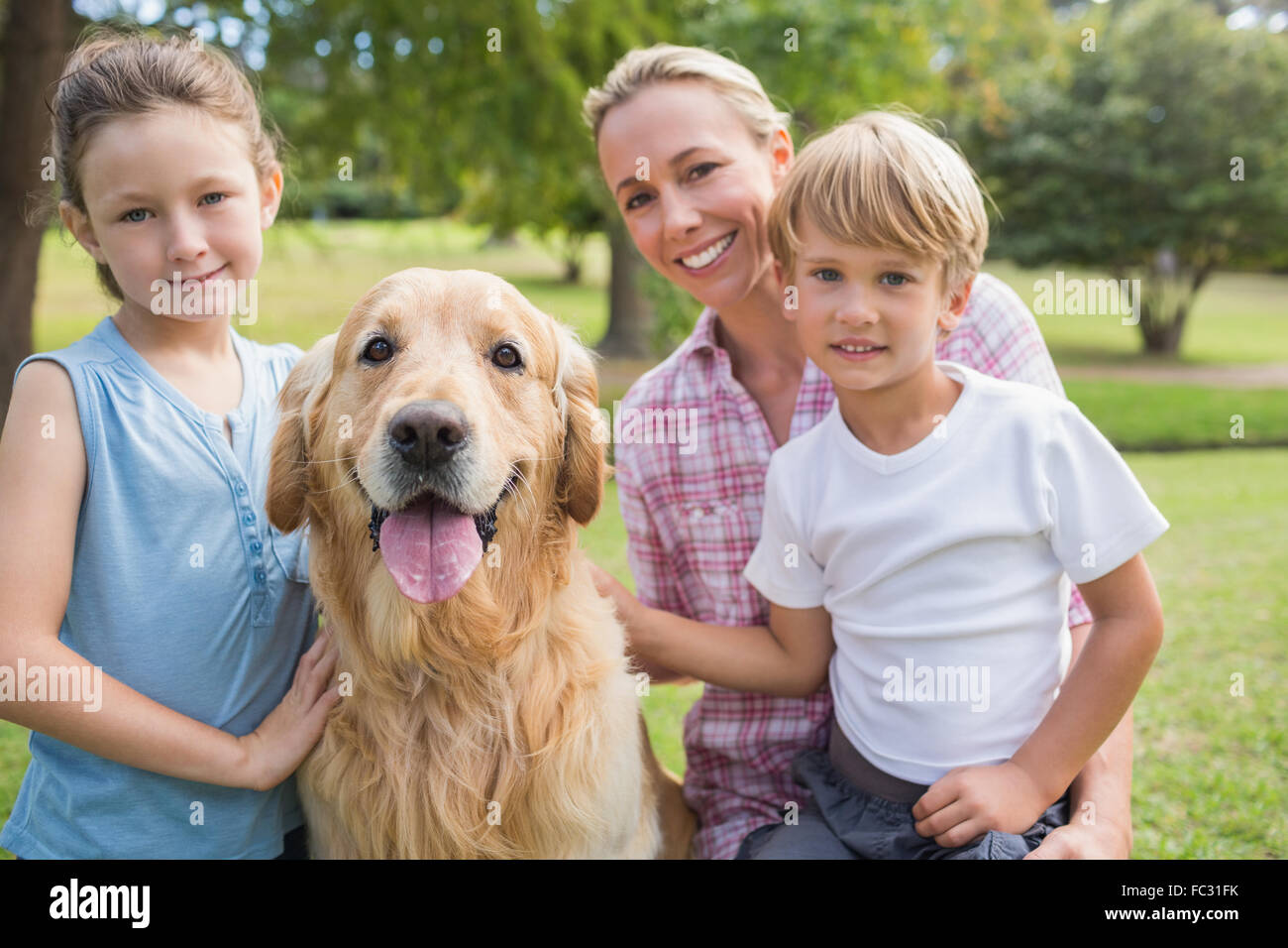 Happy family looking at camera and playing with their dog Stock Photo ...