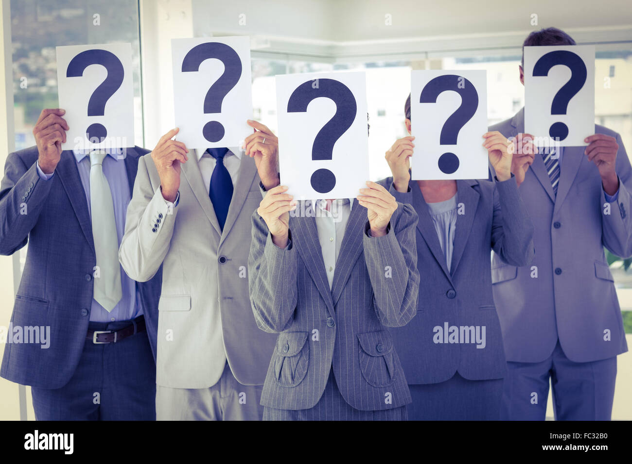 Business team holding question marks over face Stock Photo - Alamy