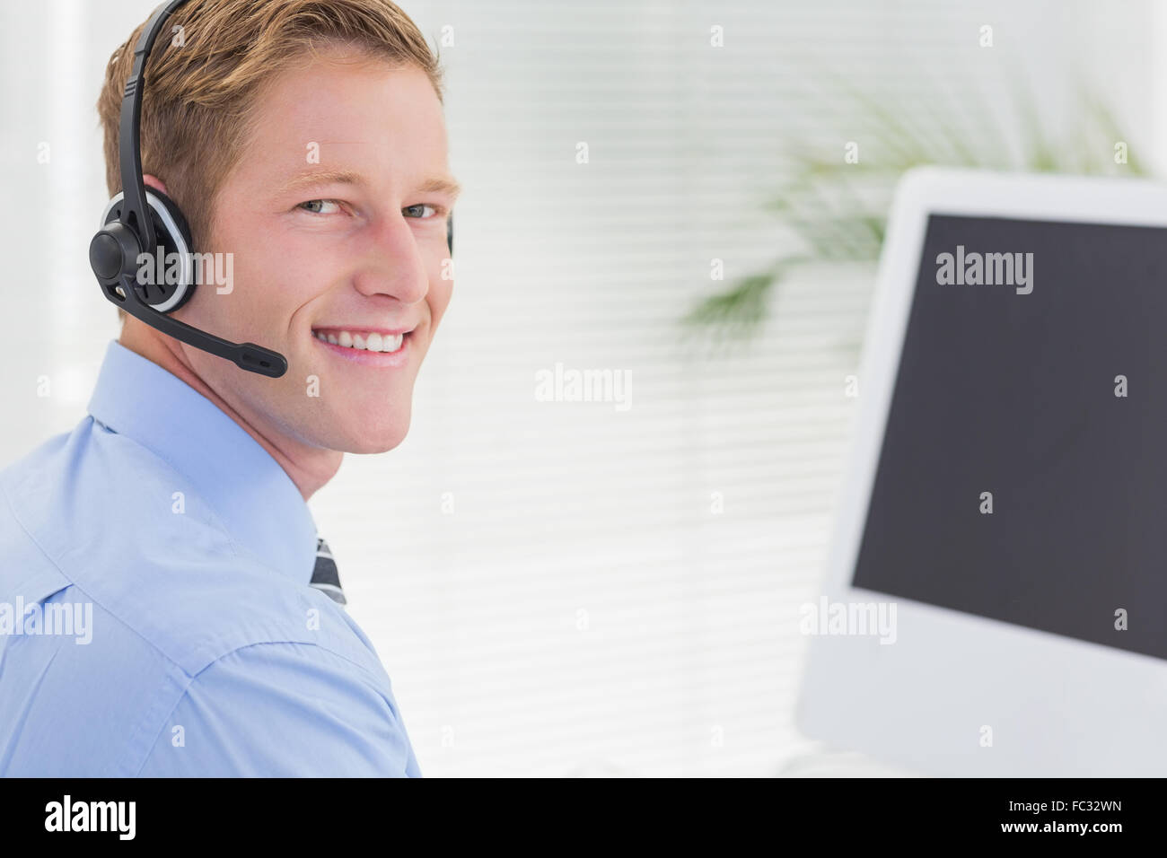 Handsome agent with headset typing on keyboard Stock Photo - Alamy