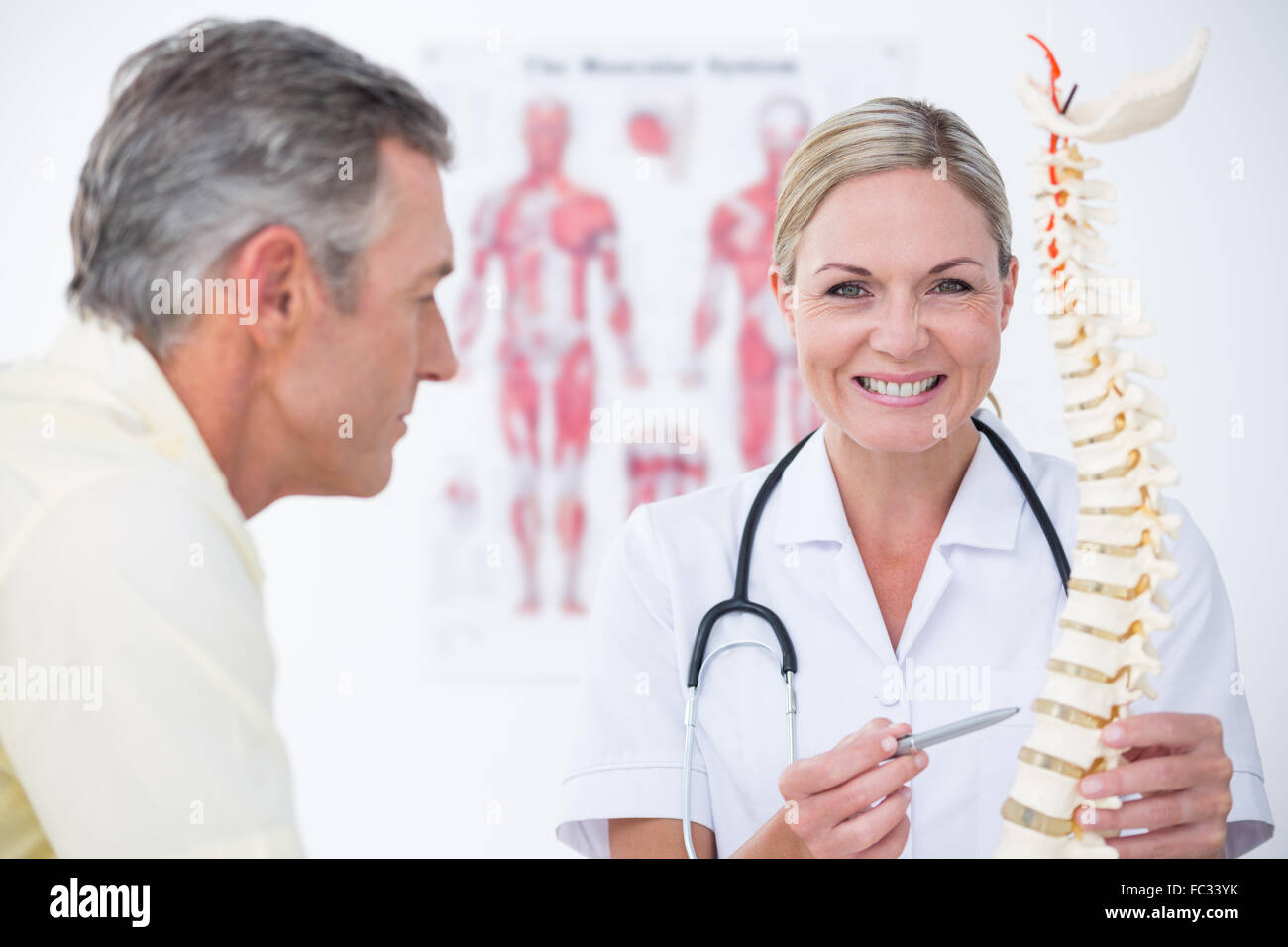 Smiling doctor showing her patient a spine model Stock Photo - Alamy