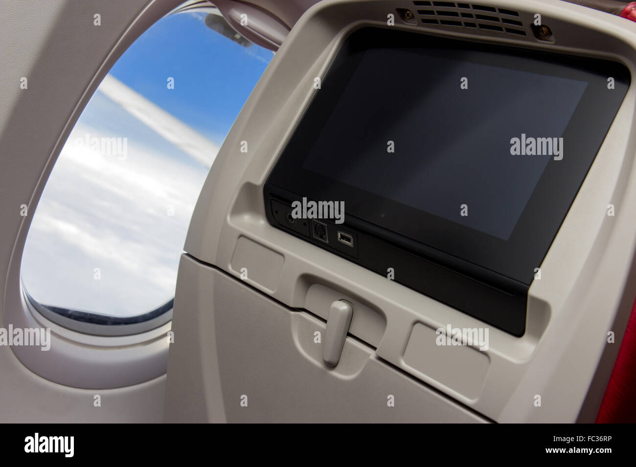 seat with a monitor beside the window of a flying airplane Stock Photo ...