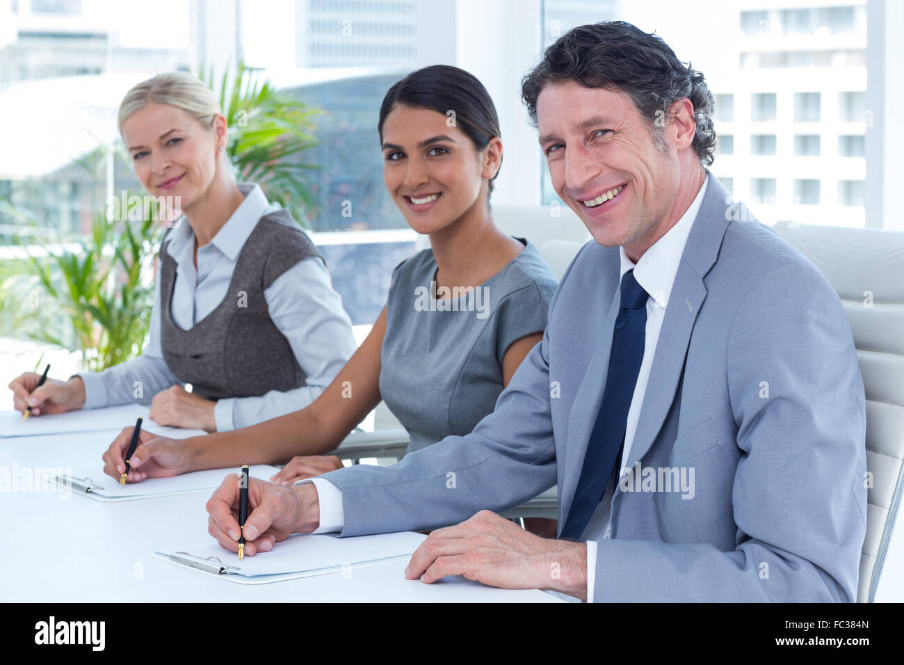 Smiling group of business people taking notes Stock Photo - Alamy
