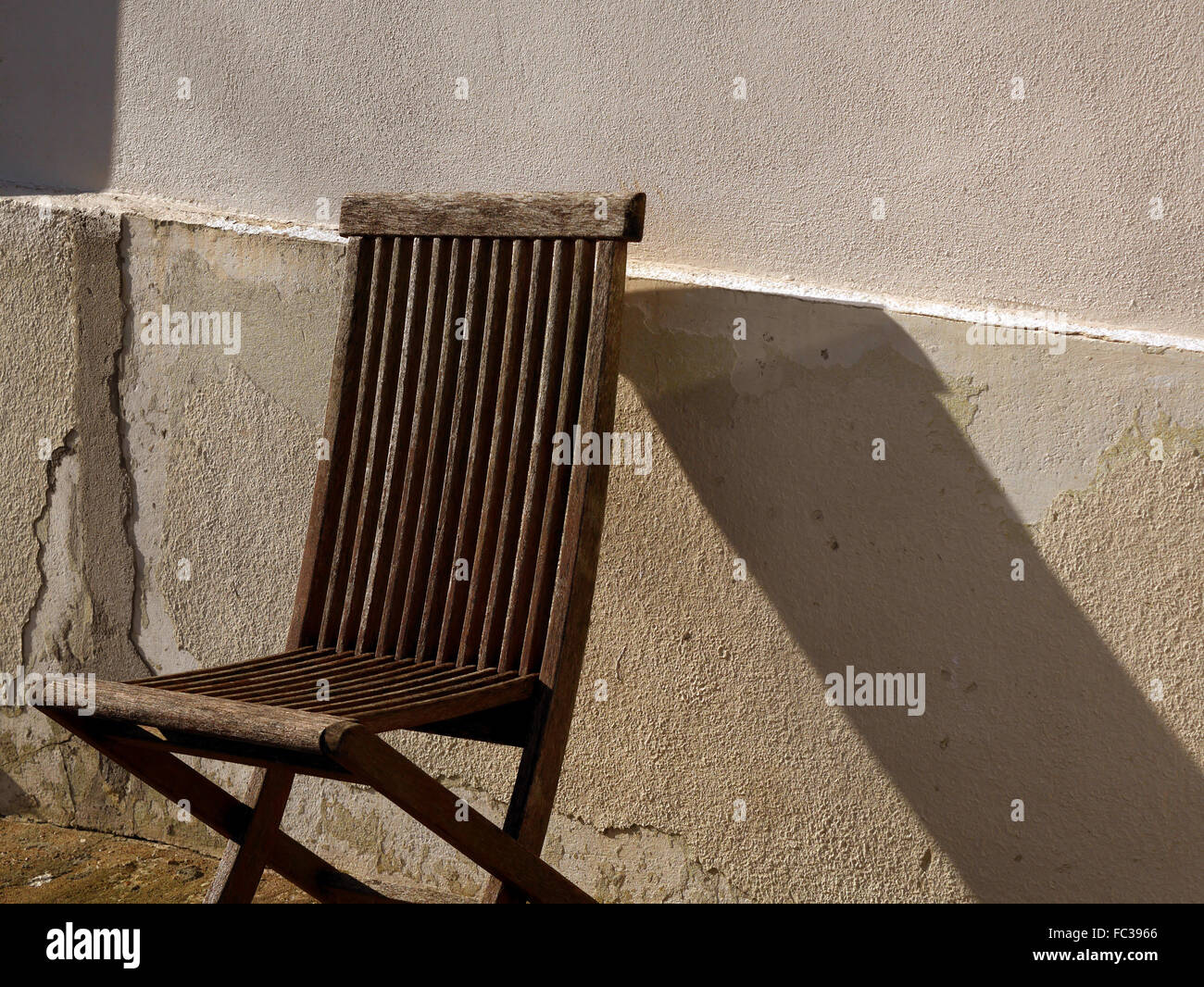 Solitary wooden chair against wall with shadows Stock Photo - Alamy