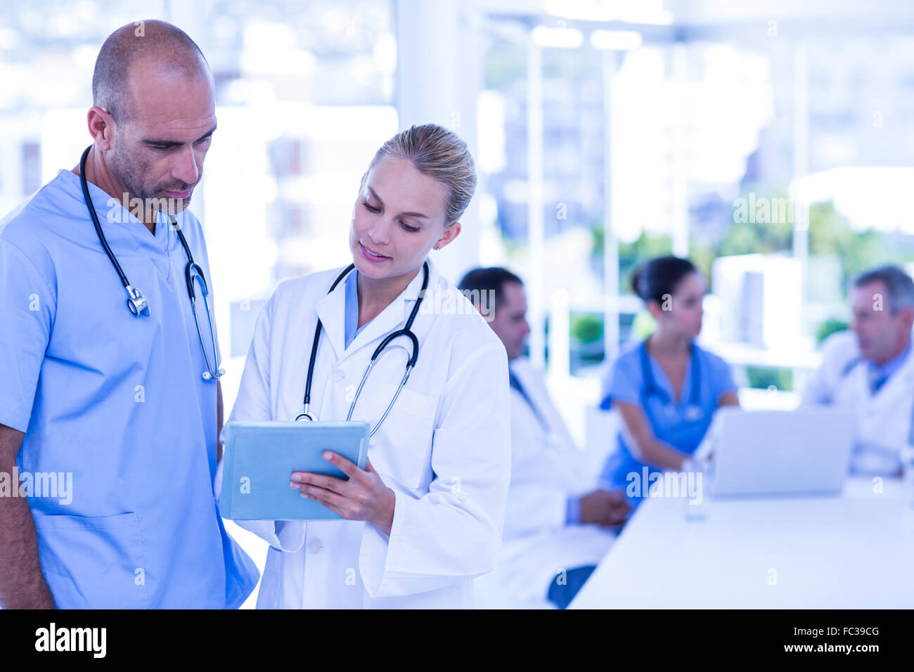 Two doctors looking at clipboard while their colleagues working Stock ...
