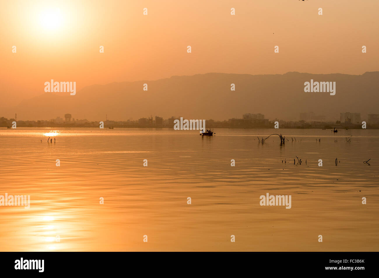Golden sunset at Ana Sagar lake in Ajmer, India with silhouettes of ...