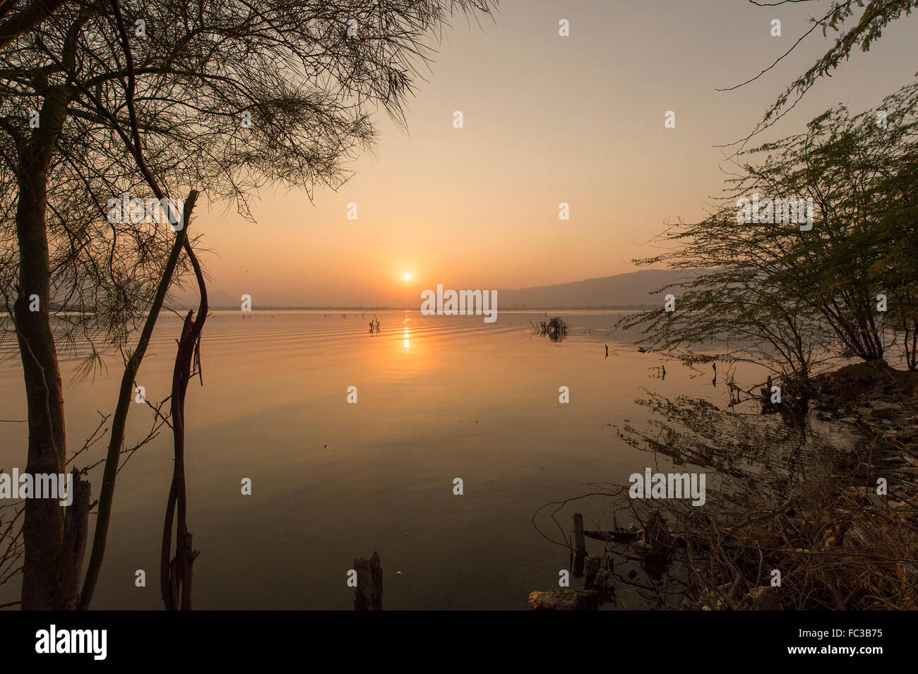 Golden sunset at Ana Sagar lake in Ajmer, India with silhouettes of ...