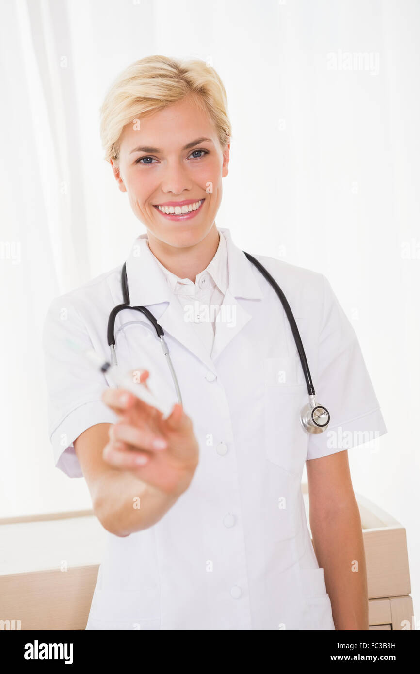 Smiling blonde doctor with syringe and stethoscope Stock Photo - Alamy