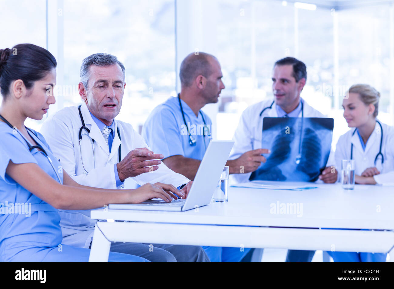 Doctors using computer whiles theirs colleagues looking at Xray Stock ...