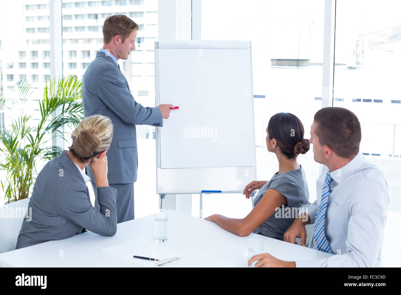 Manager presenting whiteboard to his colleagues Stock Photo - Alamy