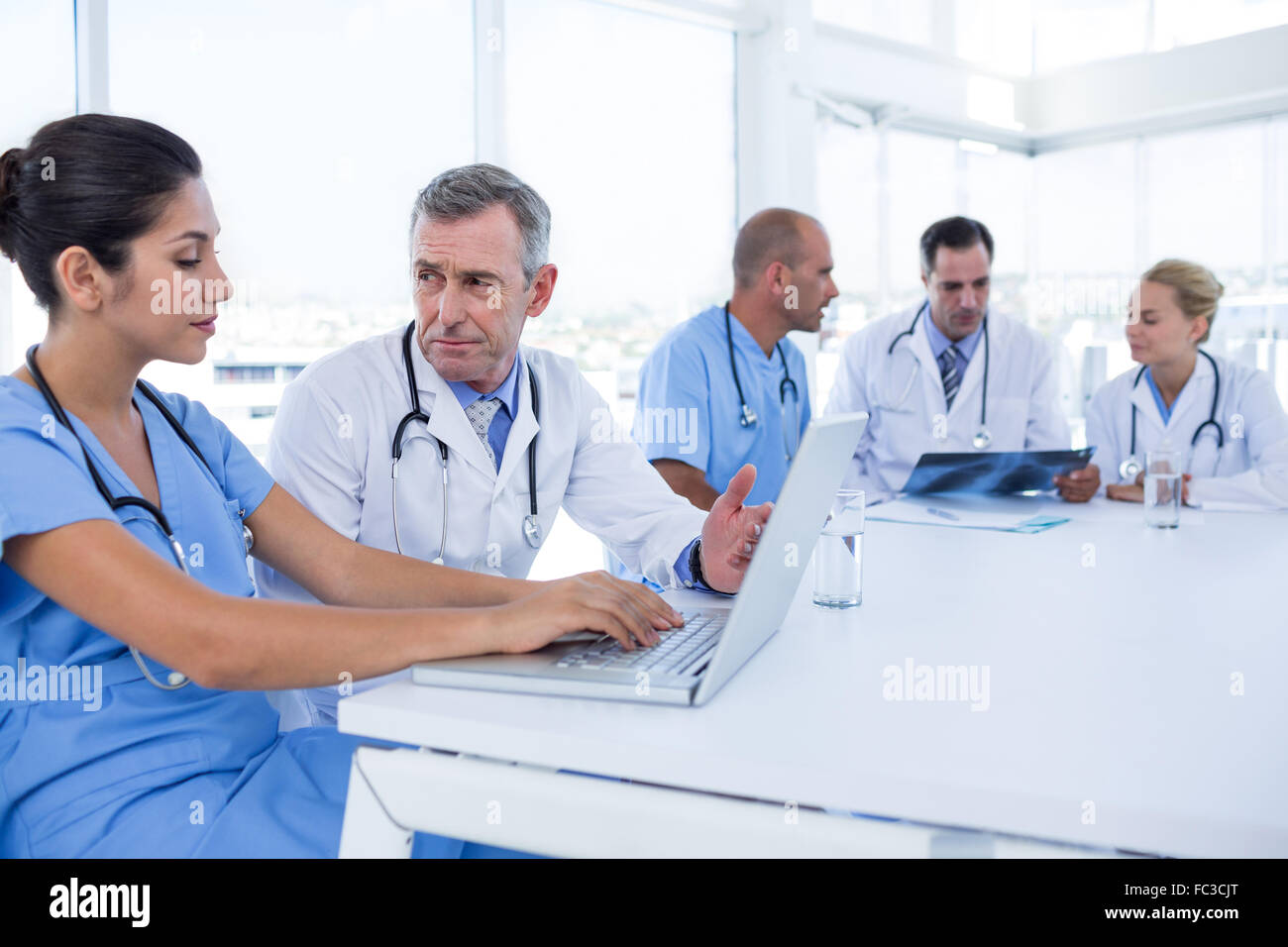 Doctors using computer whiles theirs colleagues looking at Xray Stock ...