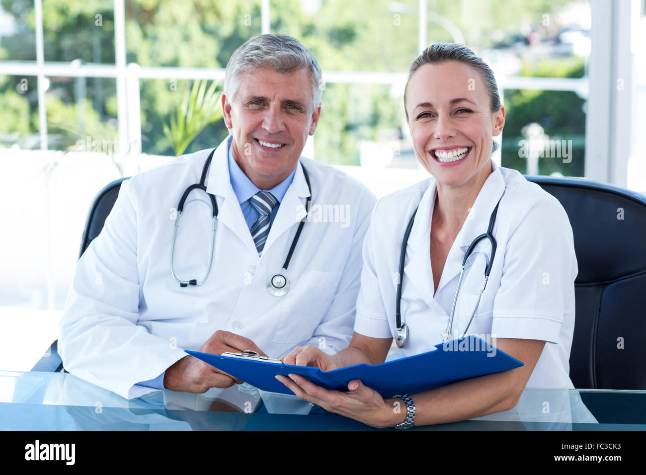 Smiling doctors working together on their file Stock Photo - Alamy