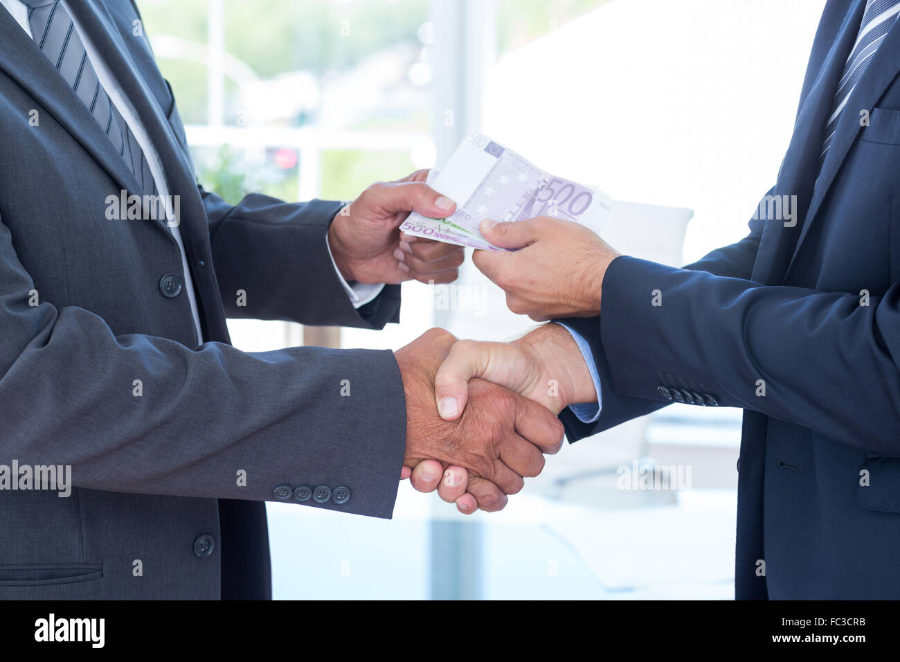 Businessmen shaking hands and exchanging money Stock Photo - Alamy
