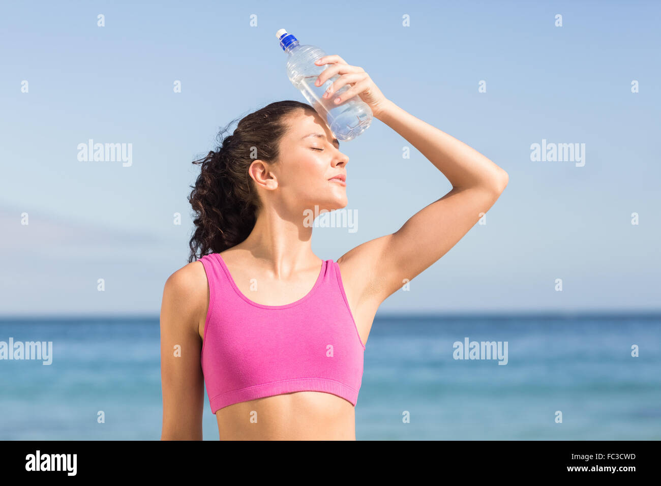 Beautiful brunette putting water bottle in her head Stock Photo - Alamy