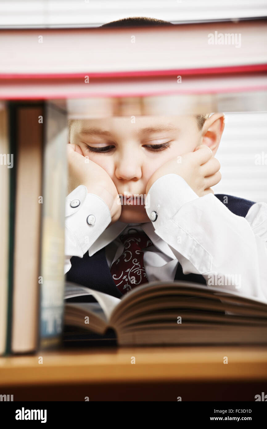 Boy behind books reading Stock Photo - Alamy