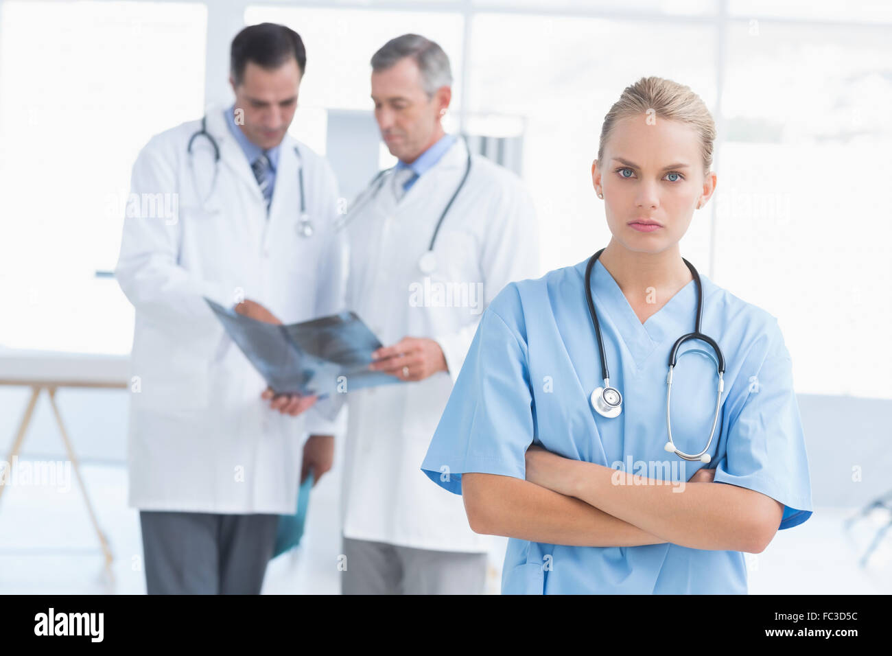 Irritated doctor looking at camera while her colleagues works Stock ...