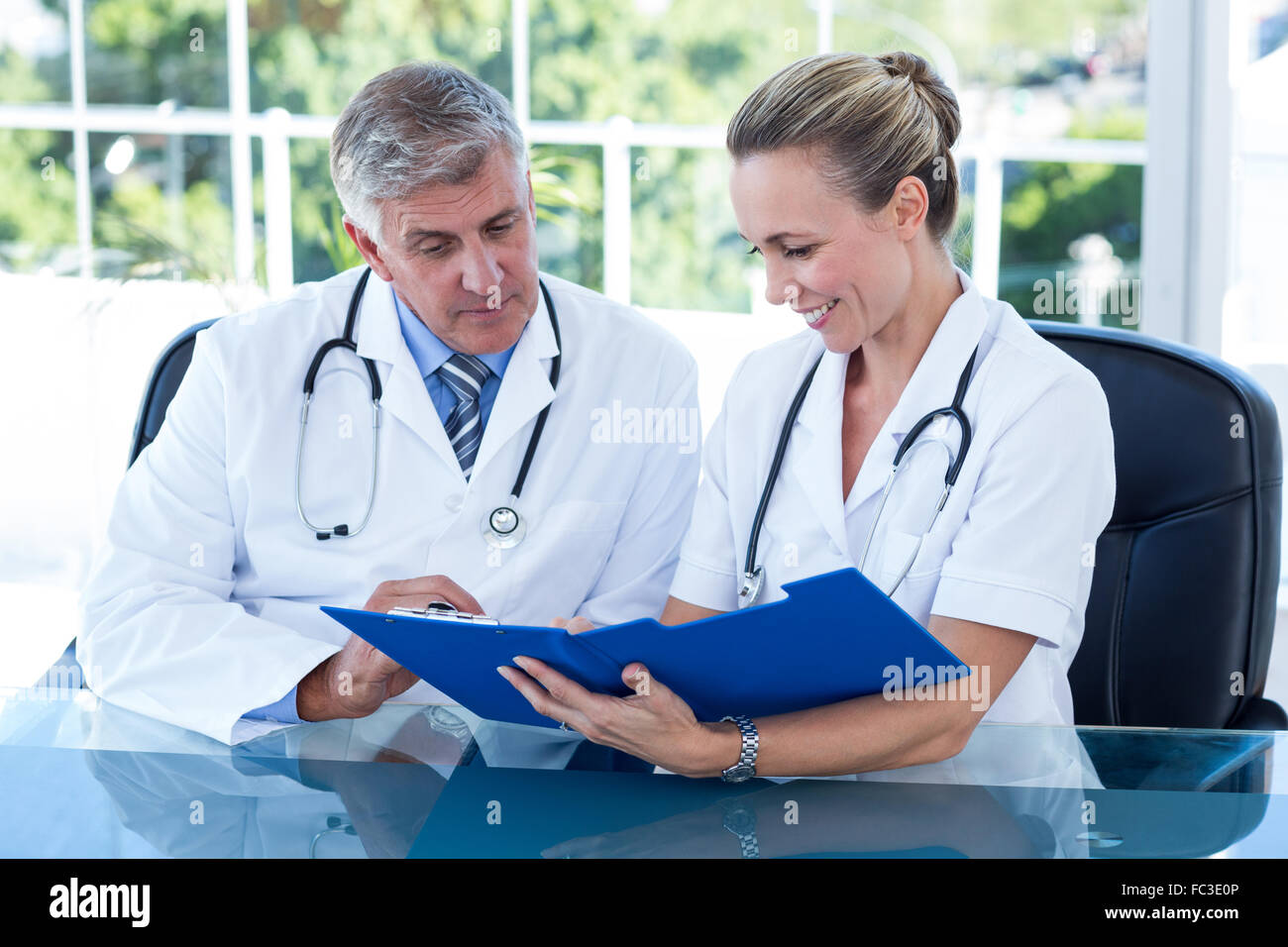 Smiling doctors working together on their file Stock Photo - Alamy