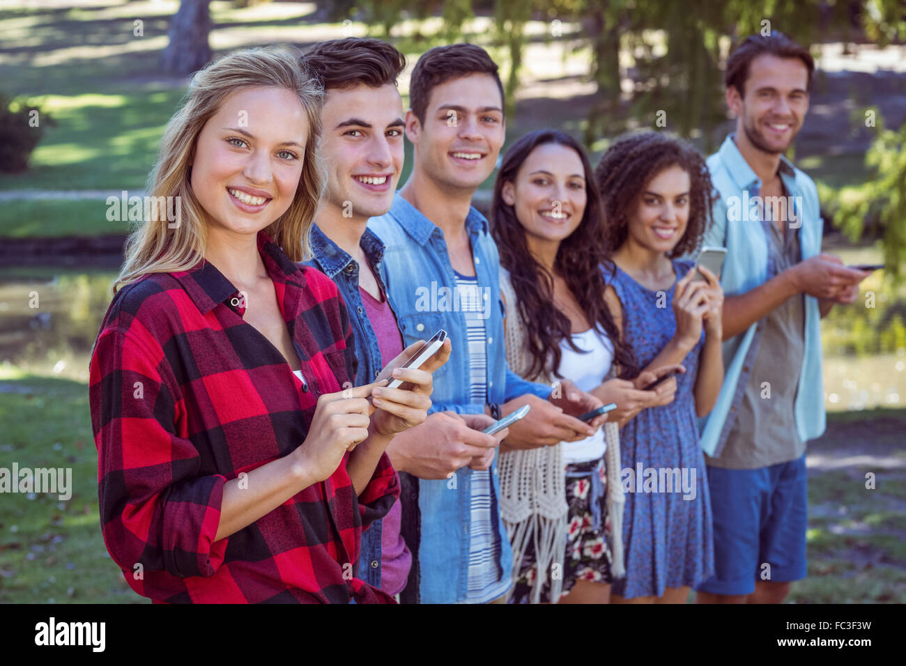 Happy friends in the park using their phones Stock Photo - Alamy