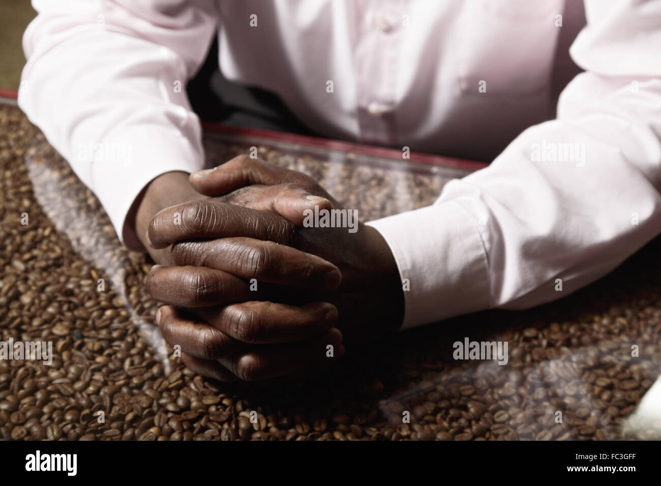 Clasped hands on tabletop Stock Photo - Alamy