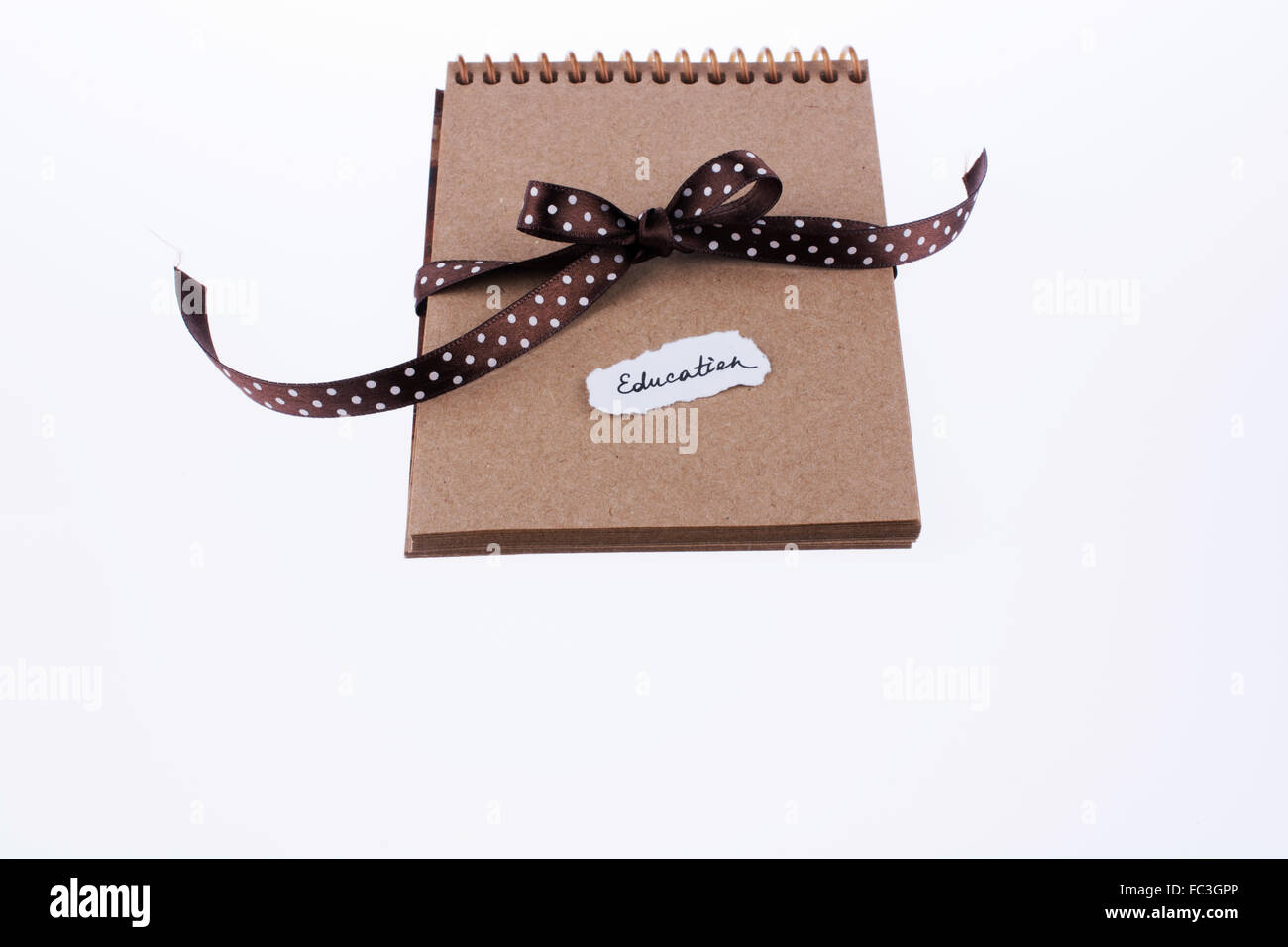 Spiral notebook with a ribbon and education note on white background ...