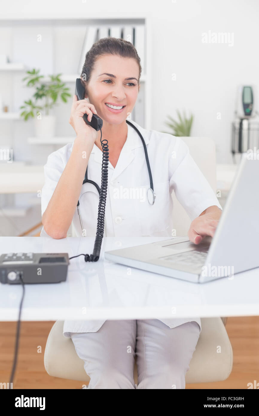 Doctor doing phone call while she using computer Stock Photo - Alamy