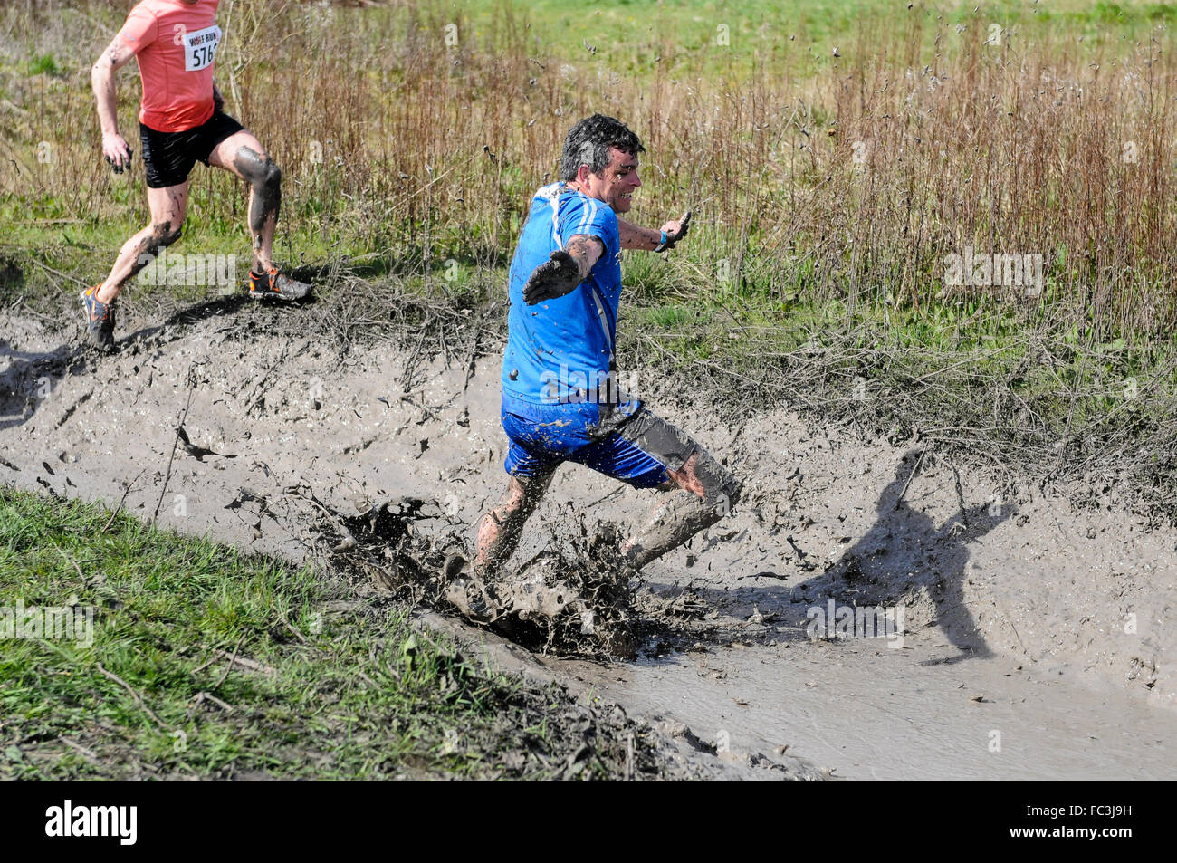 Runners crossing muddy obstacles at obstacle course race, UK Stock ...