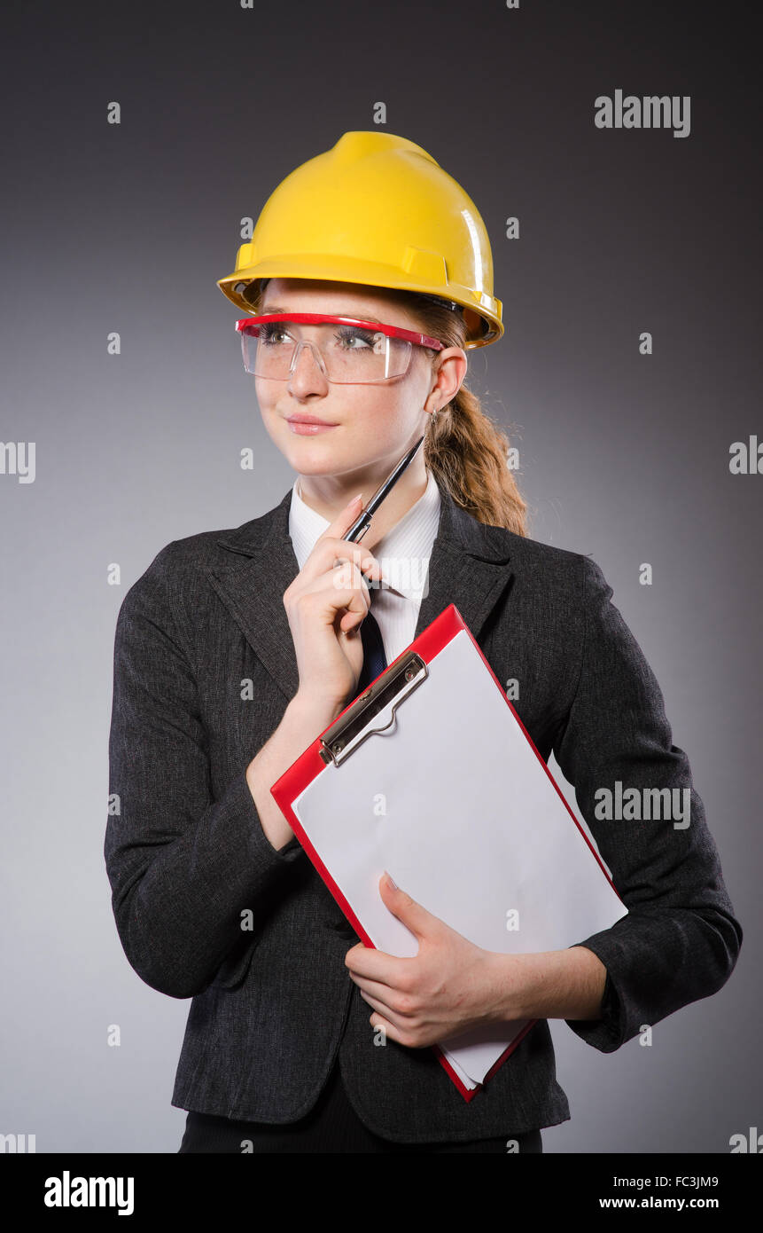 Female engineer with helmet and paper isolated on gray Stock Photo - Alamy