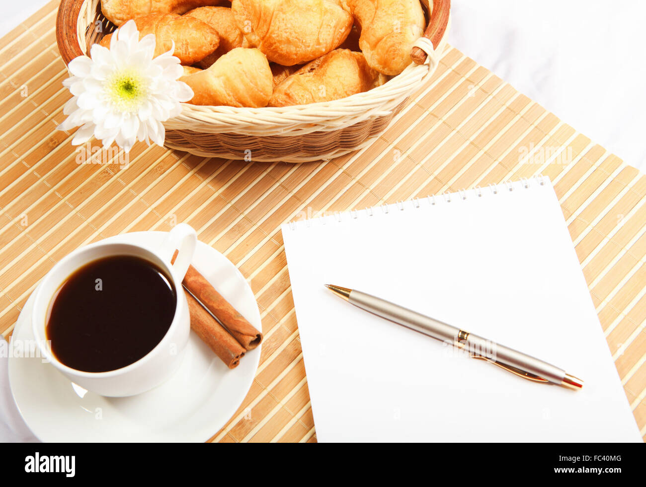 Breakfast coffee and croissants on a light background with a notebook ...