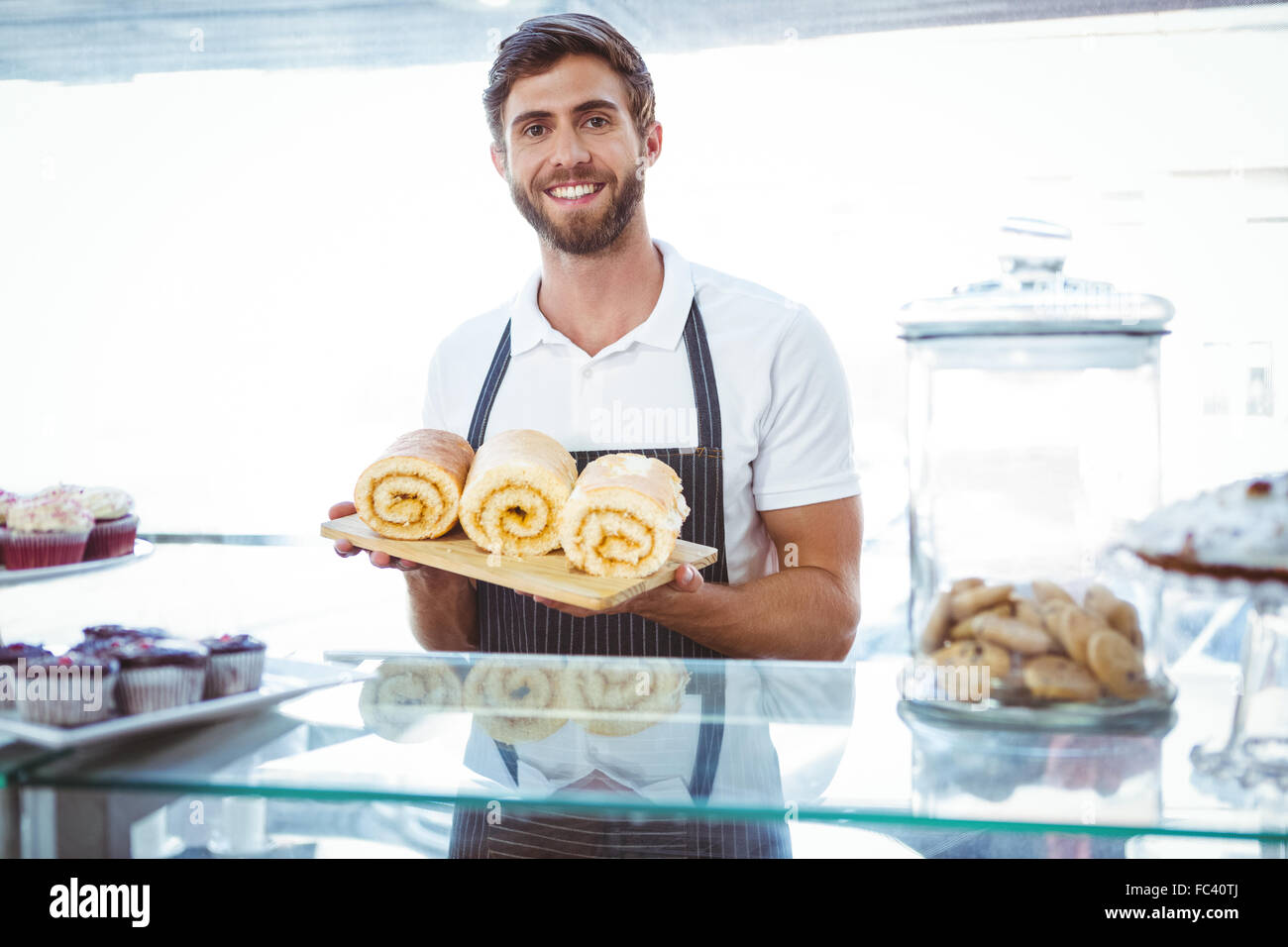 Smiling worker holding pastry behind the counter Stock Photo - Alamy