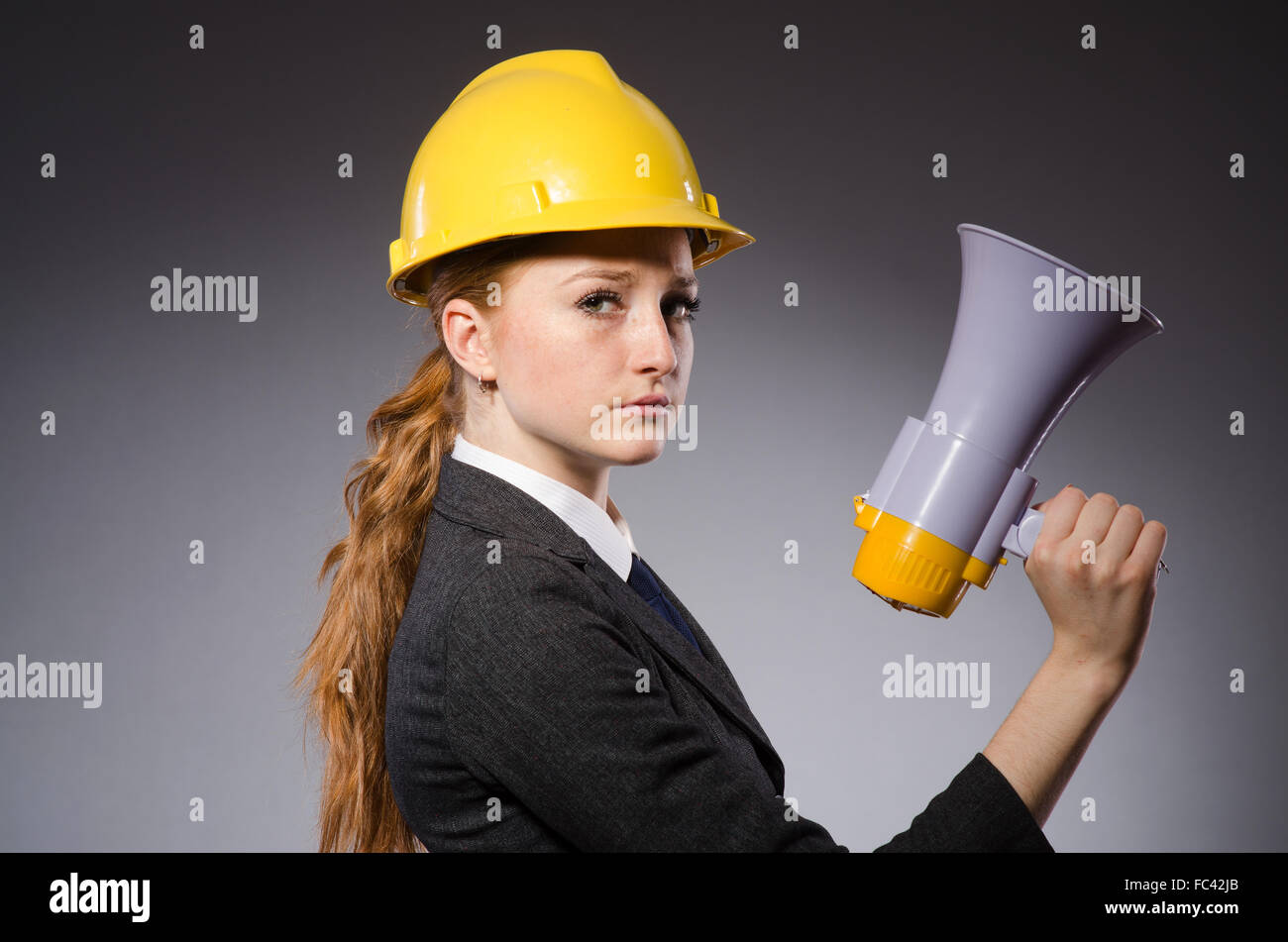 Female engineer with helmet and loudspeaker isolated on gray Stock ...