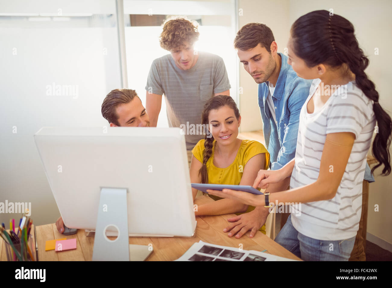 Creative business team gathered around a tablet Stock Photo - Alamy