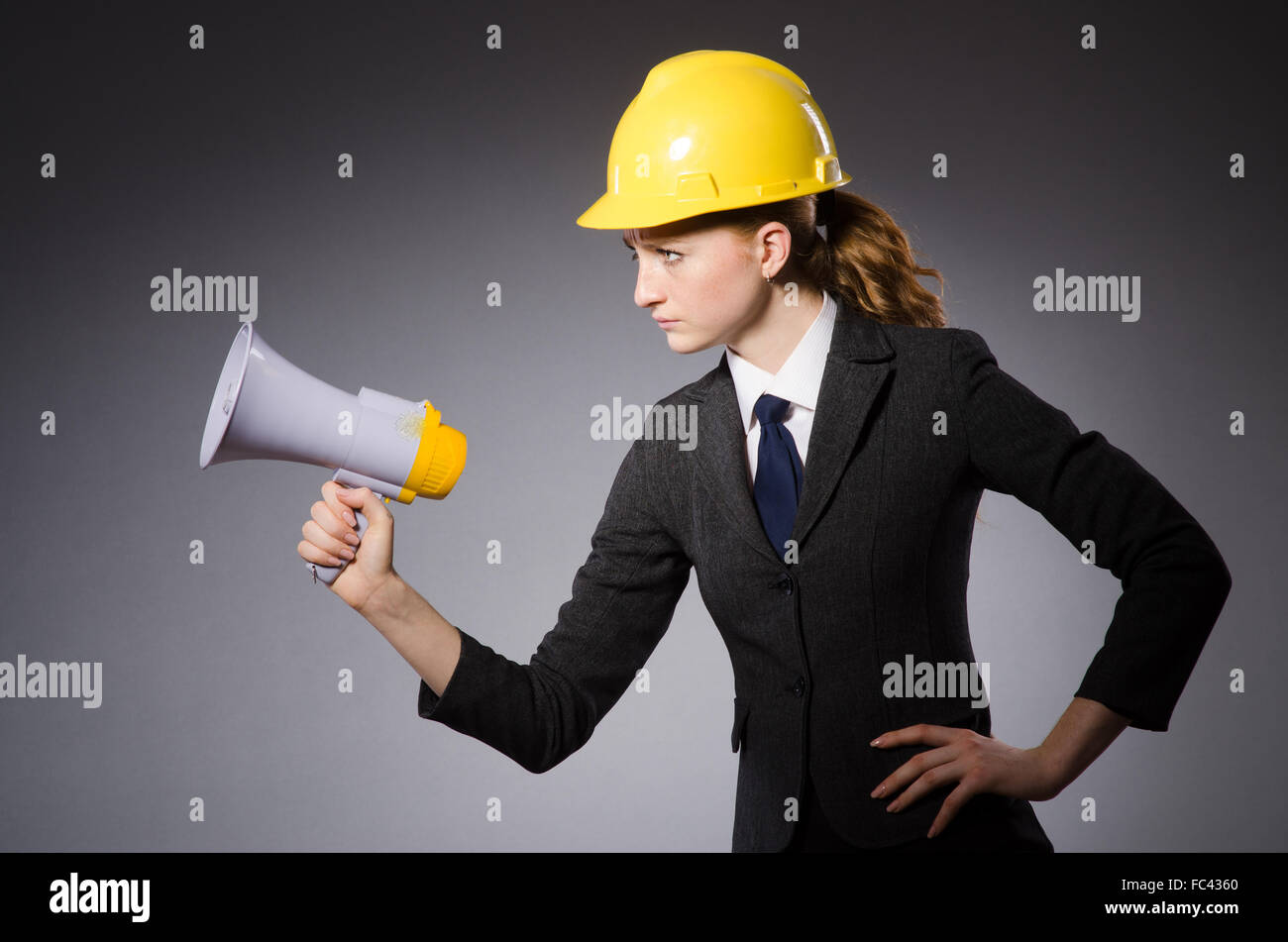 Female engineer with helmet and loudspeaker isolated on gray Stock ...