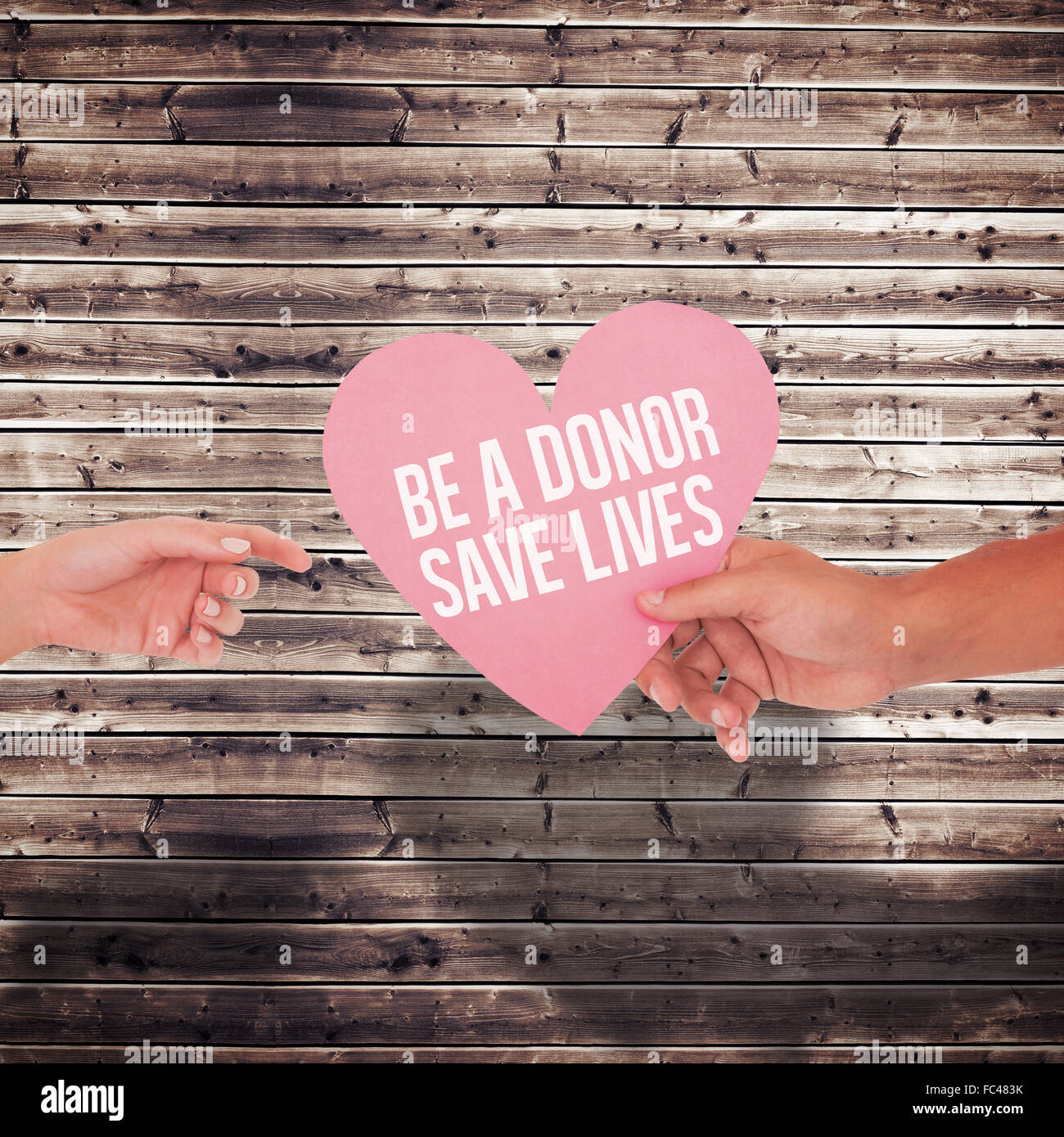 Composite image of couple passing a paper heart Stock Photo - Alamy