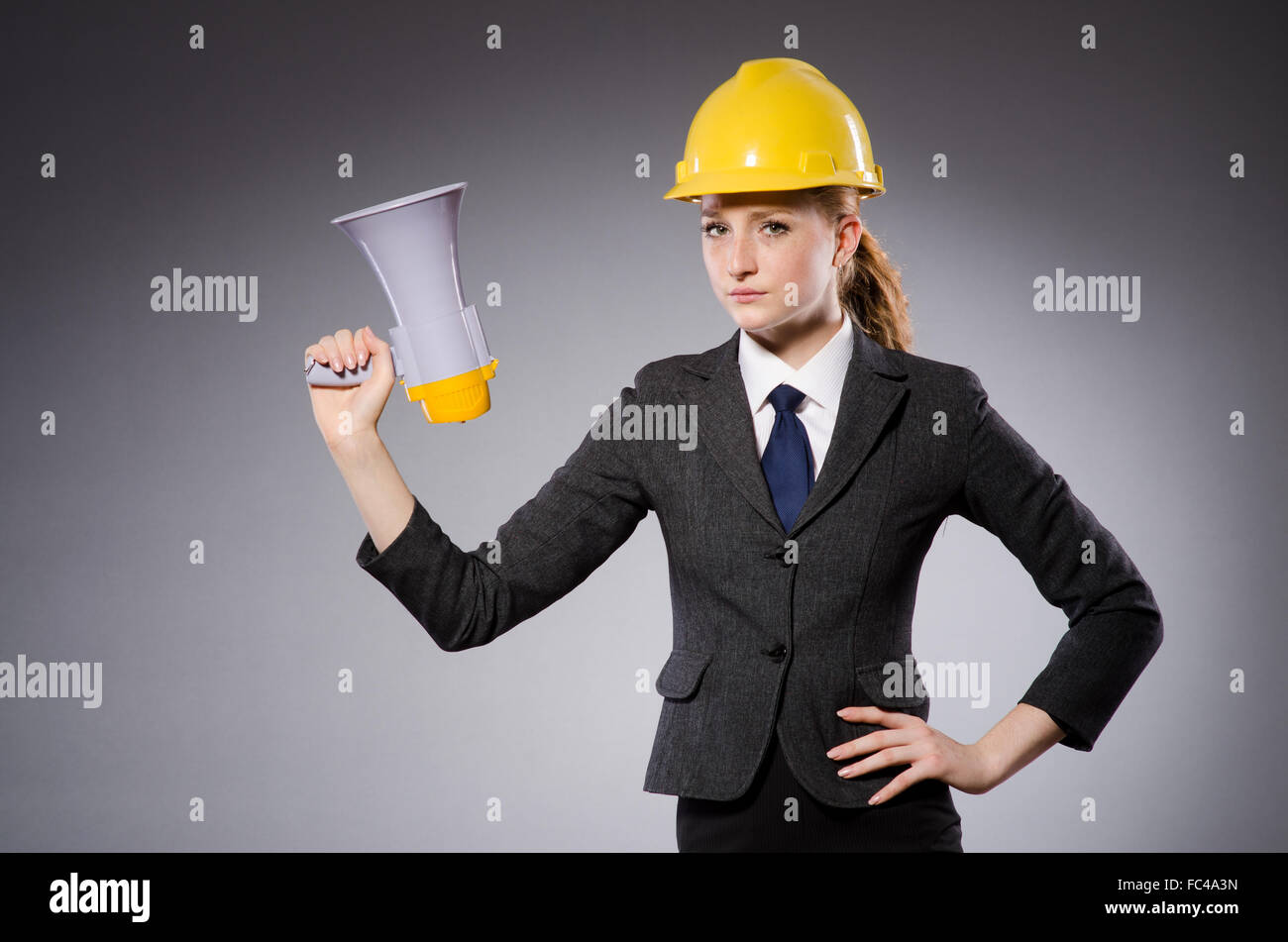 Female engineer with helmet and loudspeaker isolated on gray Stock ...