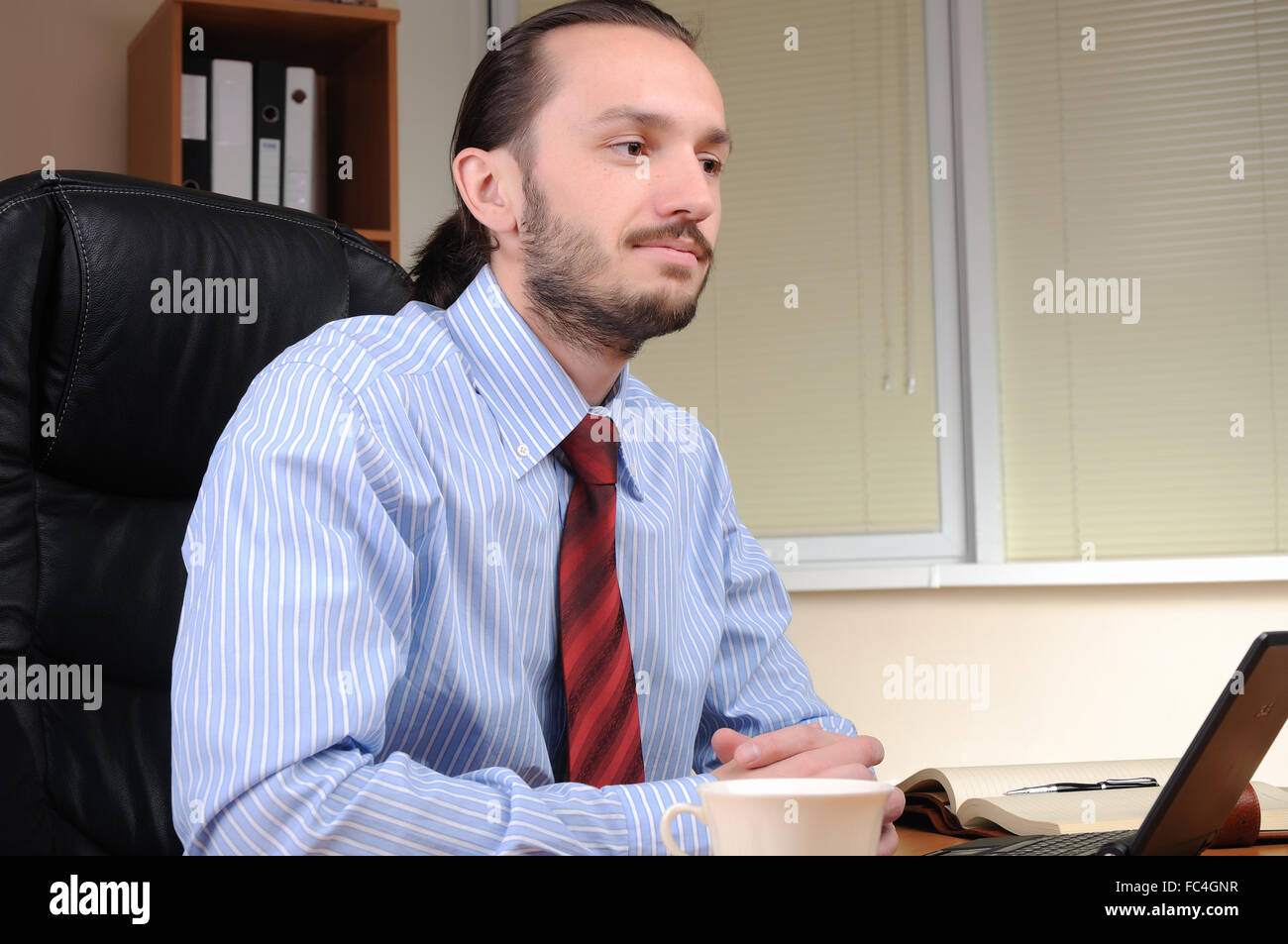 A young business man working in an office at his workplace Stock Photo ...