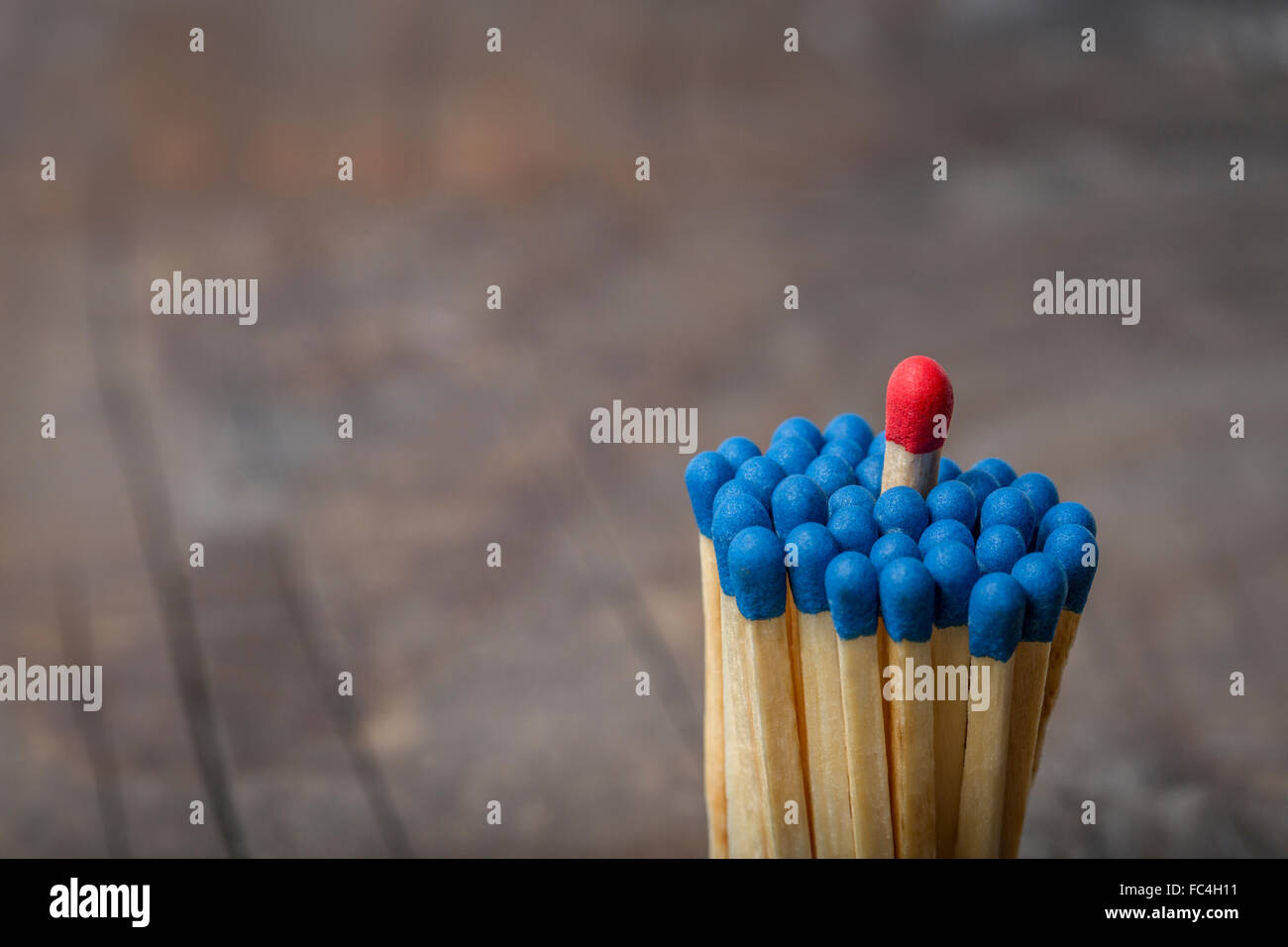 Group of blue matches with one red match stickung out on rustic wooden ...