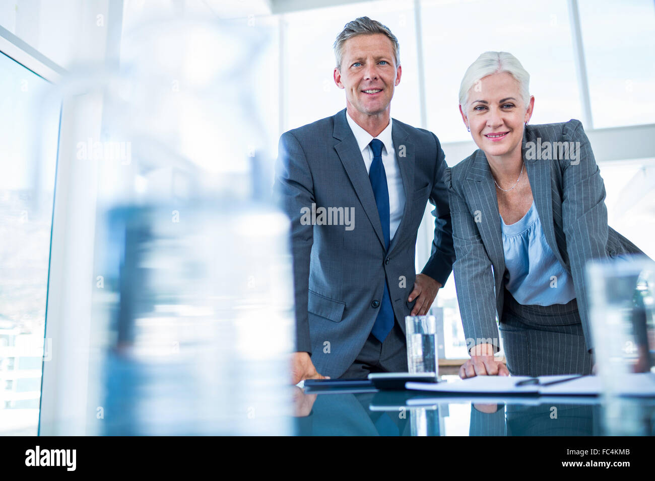 Business people looking at camera behind desk Stock Photo - Alamy