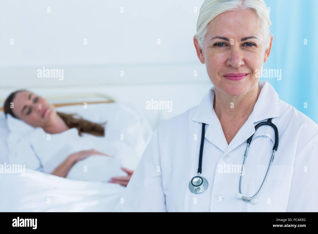 Female doctor smiling at camera while her patient sleeping Stock Photo ...