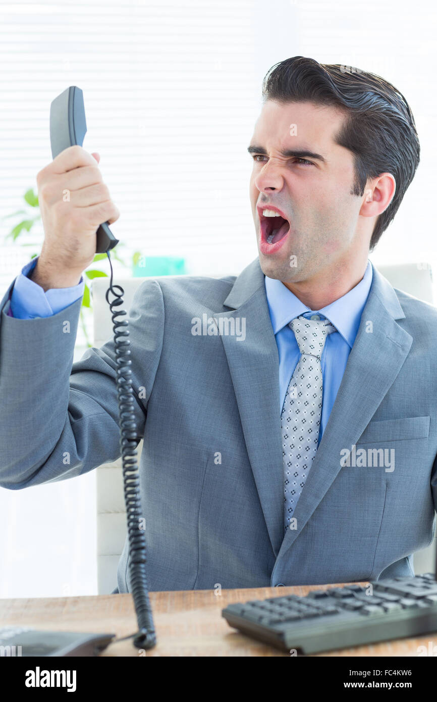 Businessman shouting as he holds out phone at office Stock Photo - Alamy