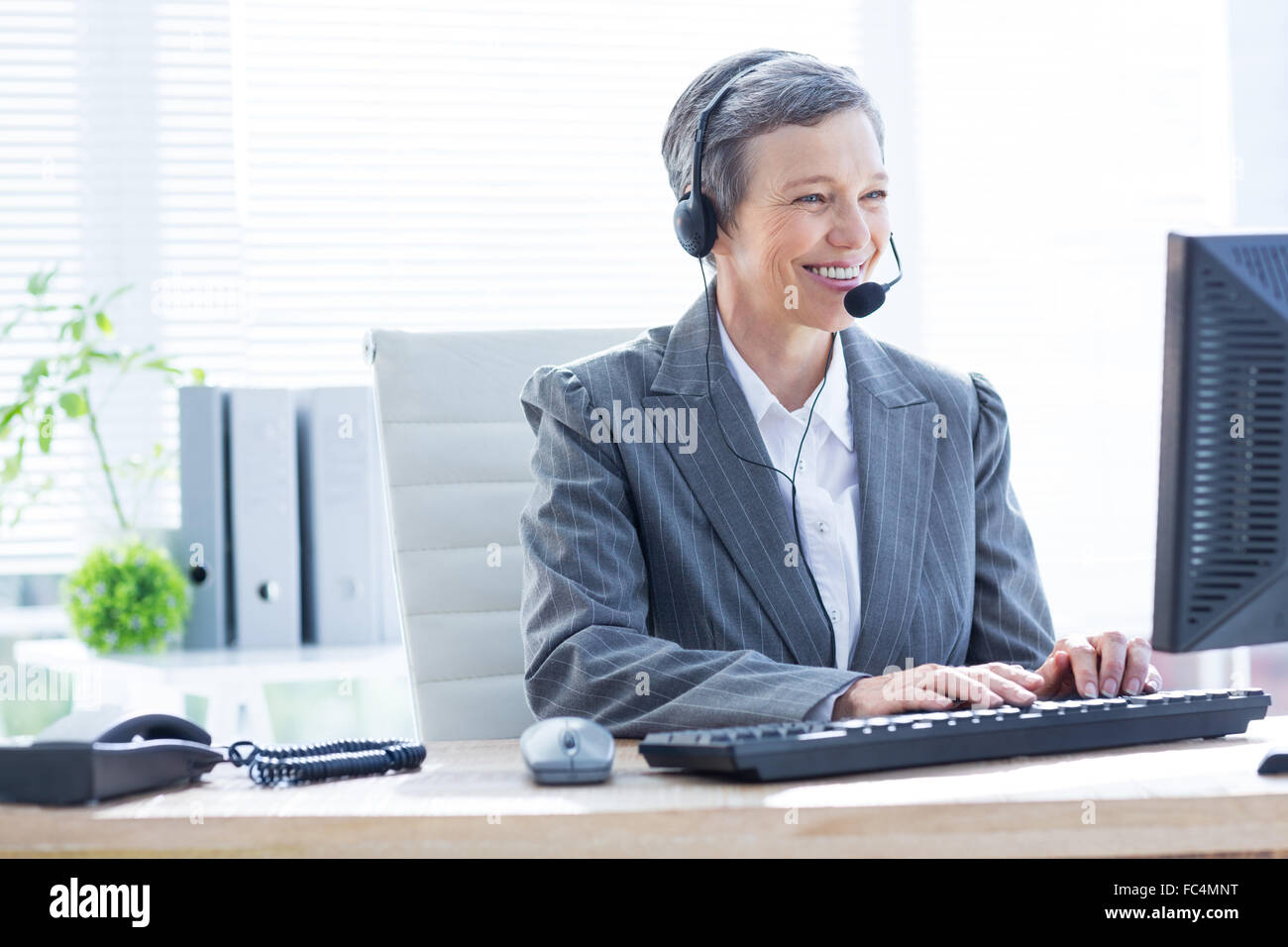 Smiling businesswoman using computer and phoning Stock Photo - Alamy